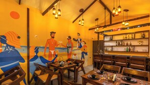 Restaurante com mobiliário de madeira, área de bar e um mural na parede.