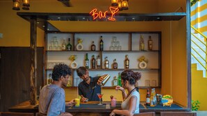 Uma área de bar com mobiliário de madeira, um letreiro de neon com a palavra 