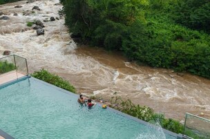 Piscina com vista para um rio agitado e vegetação densa.