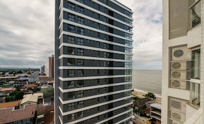 Um edifício alto com vários andares, grandes janelas e vista para o mar.