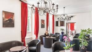 Uma área de estar moderna com poltronas de couro, uma mesa central e plantas em vasos.