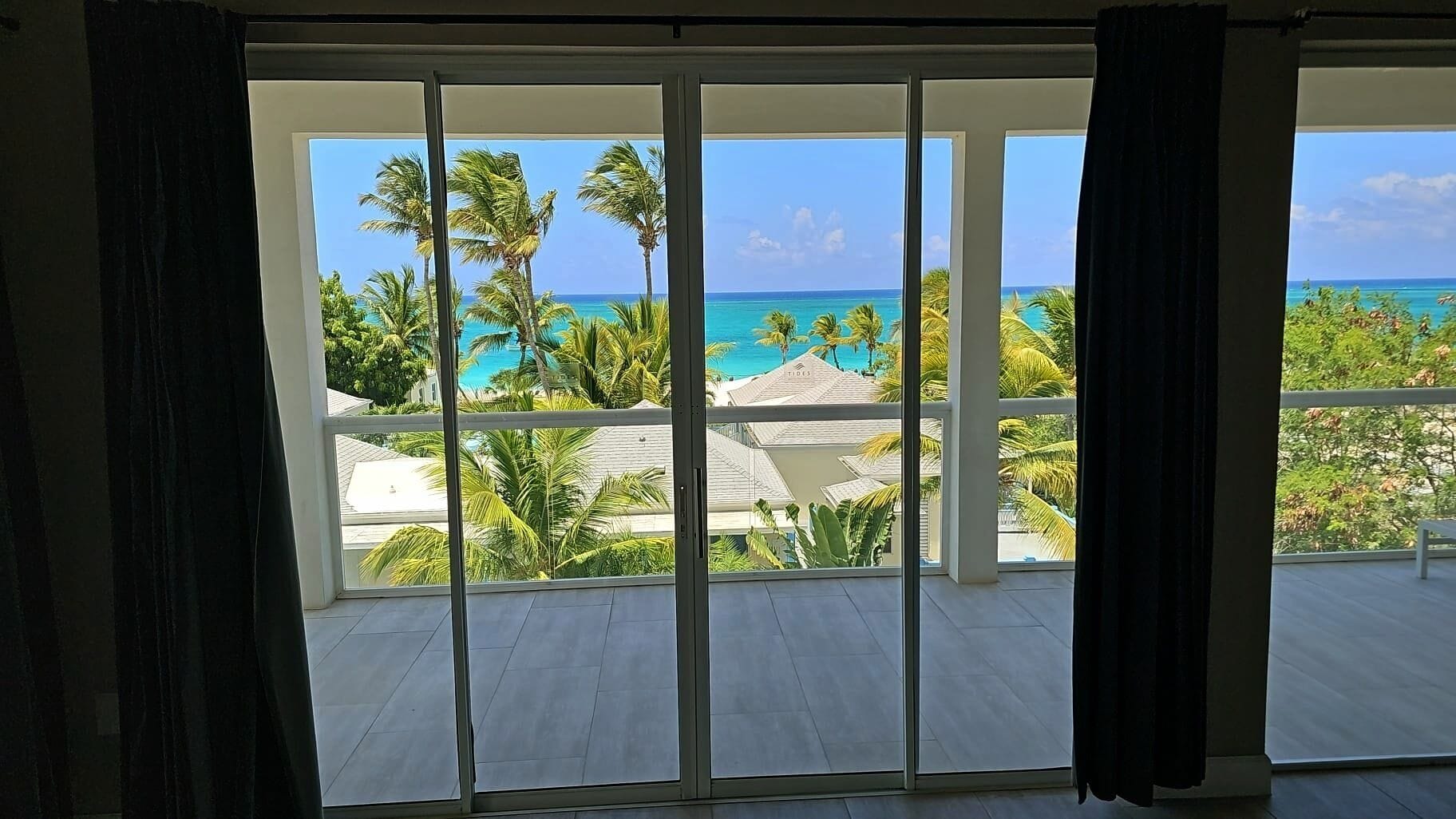 Varanda com vista para o mar e palmeiras.