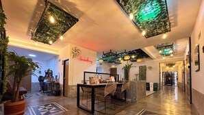 Um interior moderno com uma área de refeições central, um balcão de recepção e um corredor que leva à entrada.