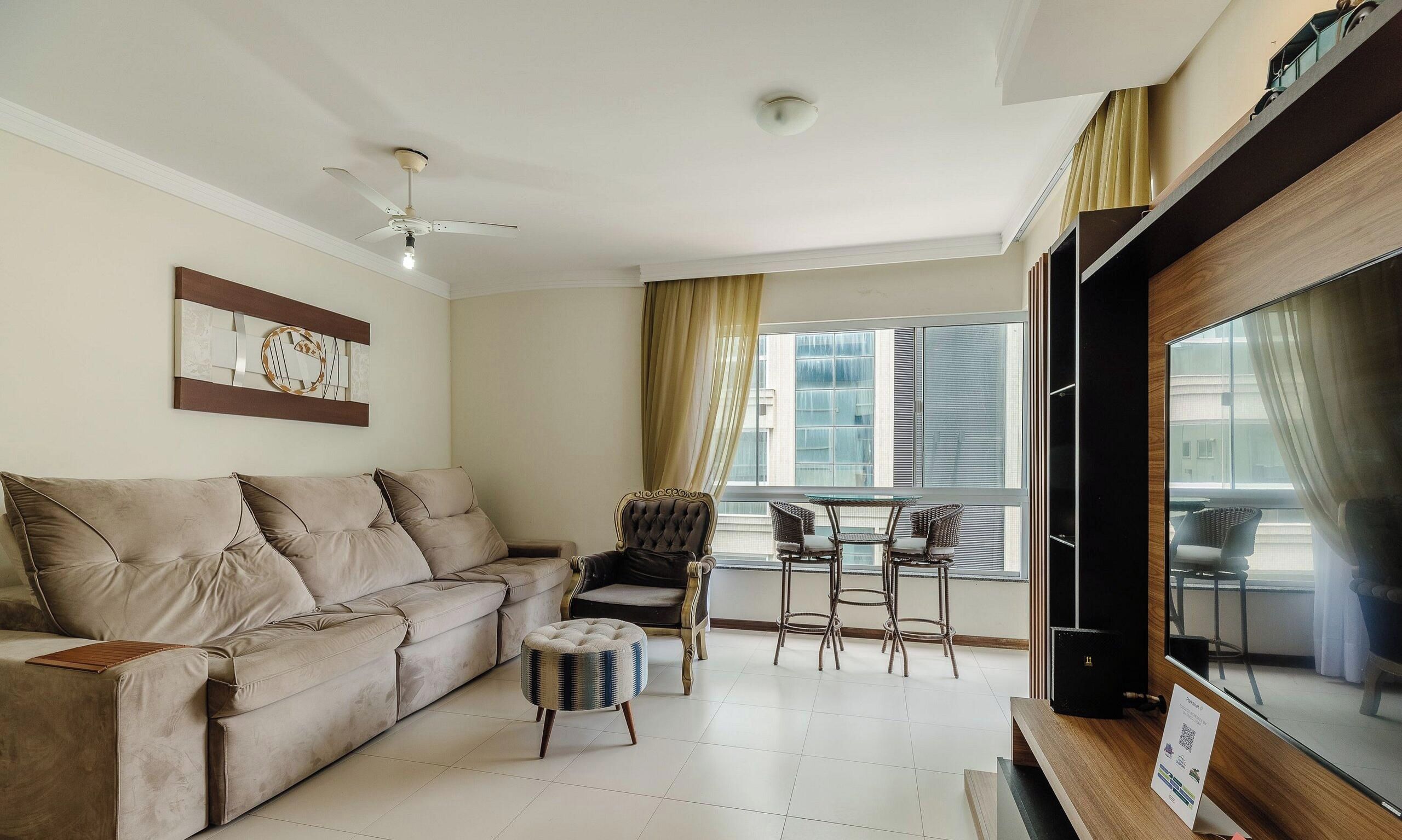 Sala de estar com sofá, pufe, poltrona e área de jantar com cadeiras e mesa.