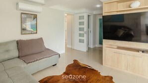 Uma sala de estar moderna com um sofá, uma TV de tela plana e um armário de madeira.