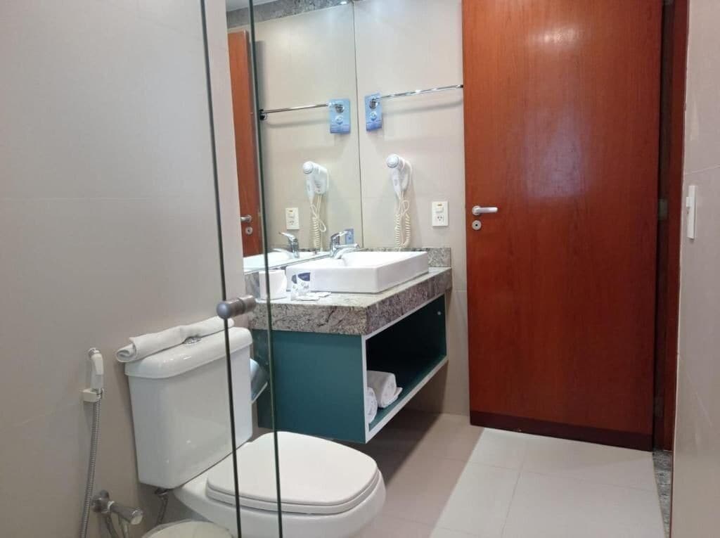 Casa de banho com sanita, lavatório e chuveiro.