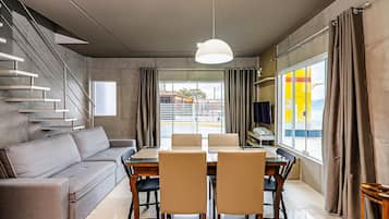 Uma sala de estar moderna com sofá, mesa de jantar, cadeiras e escada.