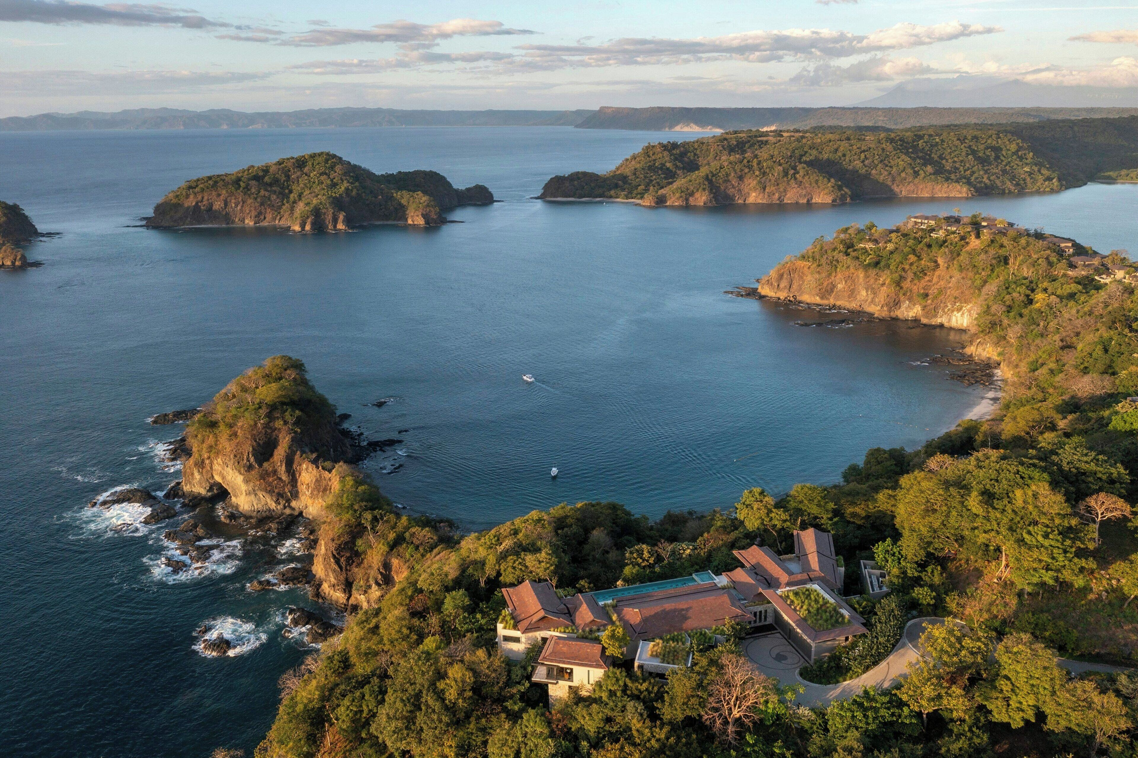 Um imóvel costeiro com vários edifícios, piscina e vista para a água e o terreno circundante.