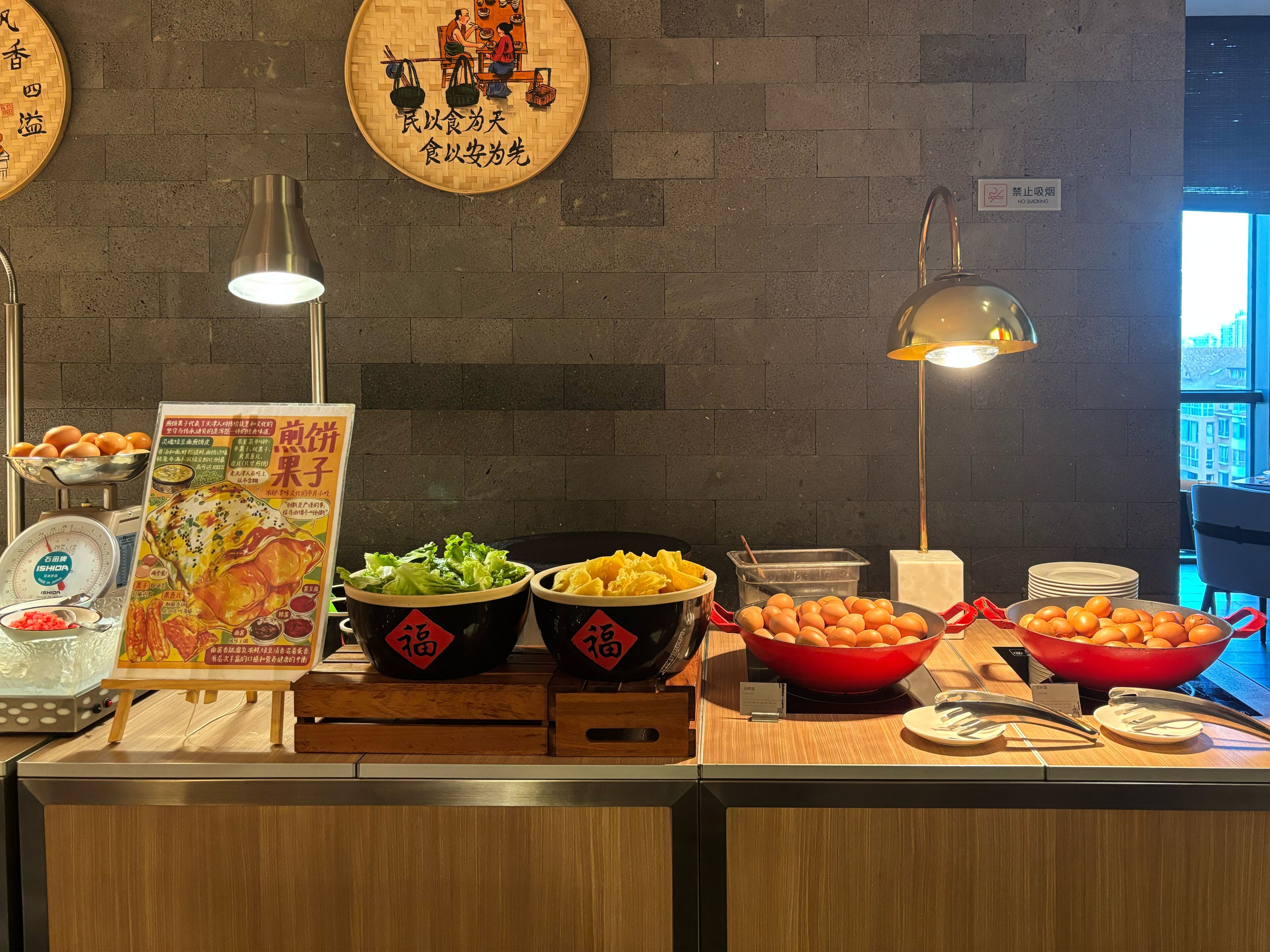 Disposição de buffet com diversos alimentos, uma balança e um cardápio.