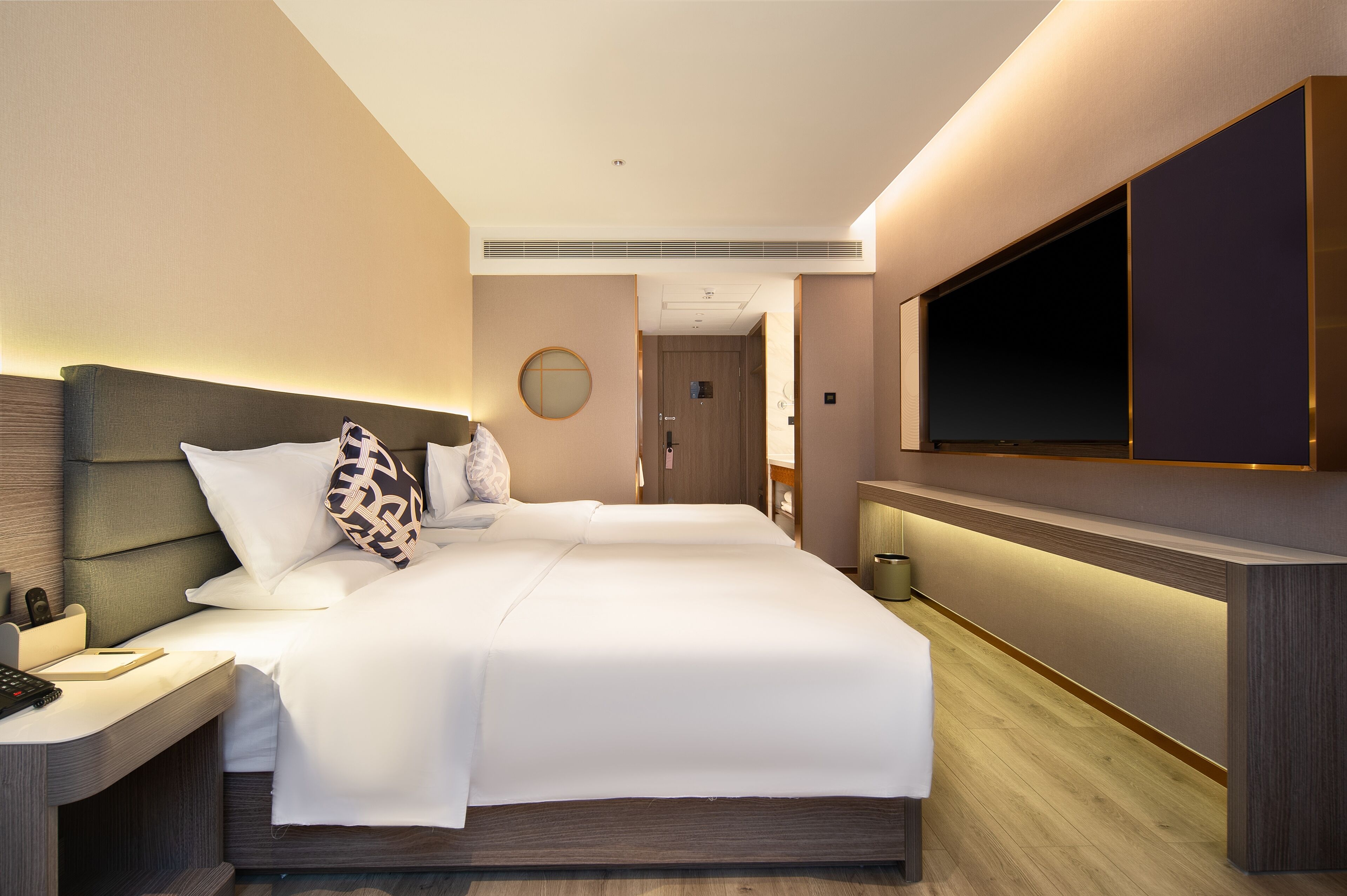 Quarto de hotel moderno com uma cama grande, mesas de cabeceira, televisão e um closet espaçoso.