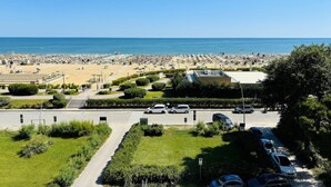 Vista costeira com praia, carros estacionados e céu limpo.