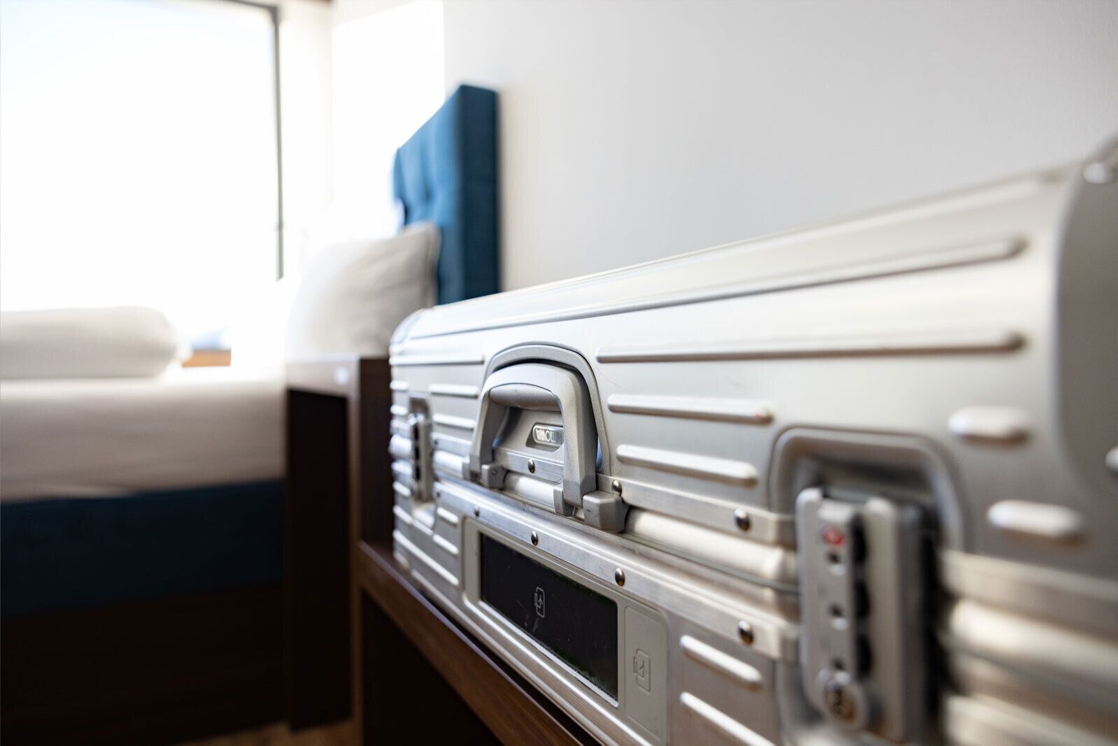 Detalhe do interior de uma caravana, destacando a cama, um painel de controle e uma janela.
