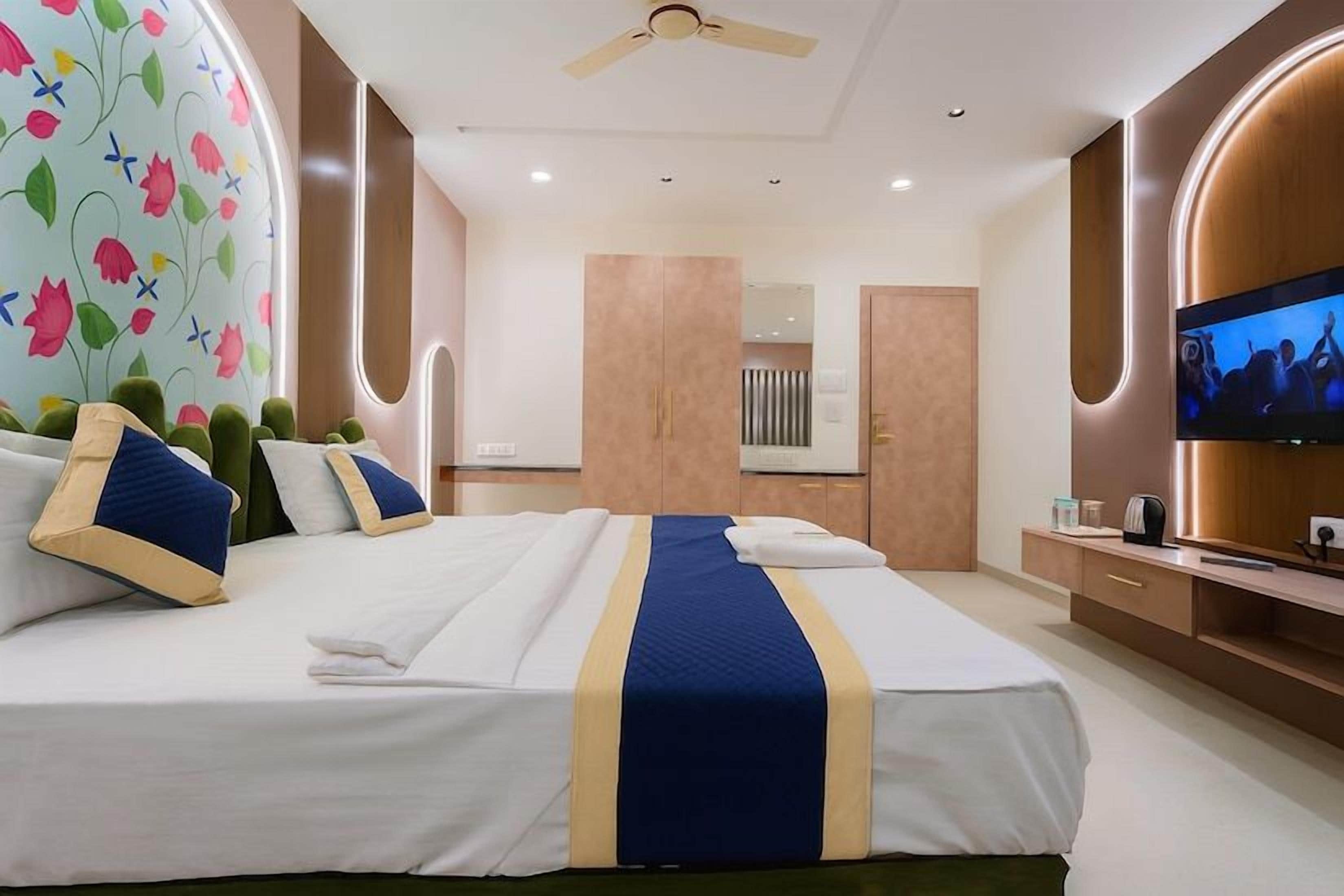 Quarto de hotel moderno com cama grande, televisão de tela plana e ventilador de teto.
