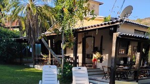 Uma área de piscina com espreguiçadeiras, uma piscina pequena e um edifício com espaço para sentar ao ar livre.