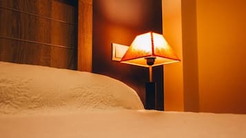 Quarto de hotel com uma cama, cabeceira de madeira e luminária fixada na parede.