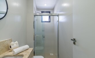 Uma casa de banho moderna com cabine de duche em vidro, sanita e lavatório com bancada de mármore.