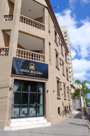 Um edifício com uma placa indicando 'VISTA IRACEMA STUDIOS' e uma placa de proibido estacionar.