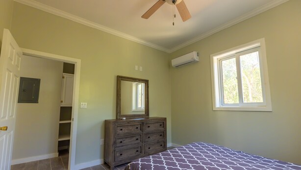 Quarto com cama, penteadeira, ventoinha no teto, janela e aparelho de ar condicionado.