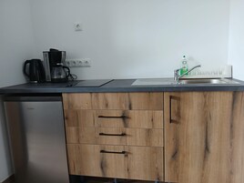 Cozinha com máquina de lavar louça Bosch, armários de madeira, pia com torneira e cafeteira.