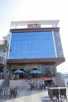 Hotel com fachada moderna, entrada visível e área de estar externa com guarda-sóis.