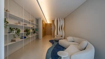 Um interior moderno com um sofá branco, um tapete azul e estantes brancas com plantas.
