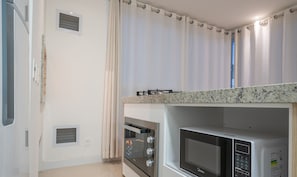 Uma cozinha compacta com forno embutido, micro-ondas e fogão a gás.