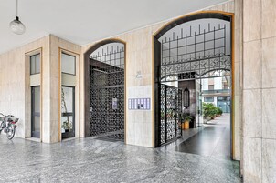 Entrada de um edifício moderno com portas arqueadas, um portão de segurança e uma bicicleta estacionada na frente.