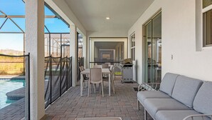Um alpendre coberto com piscina, área de jantar e um sofá.