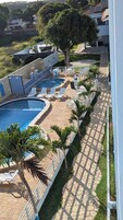 Uma área de piscina com espreguiçadeiras, piscina circular e caminho de pedra.