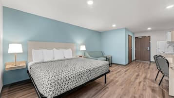 Quarto de hotel moderno com cama, mesas de cabeceira, escrivaninha e uma cadeira.