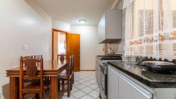 Uma cozinha com mesa e cadeiras, fogão e pia.