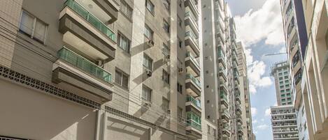 Um edifício residencial com vários andares, varandas e portão.