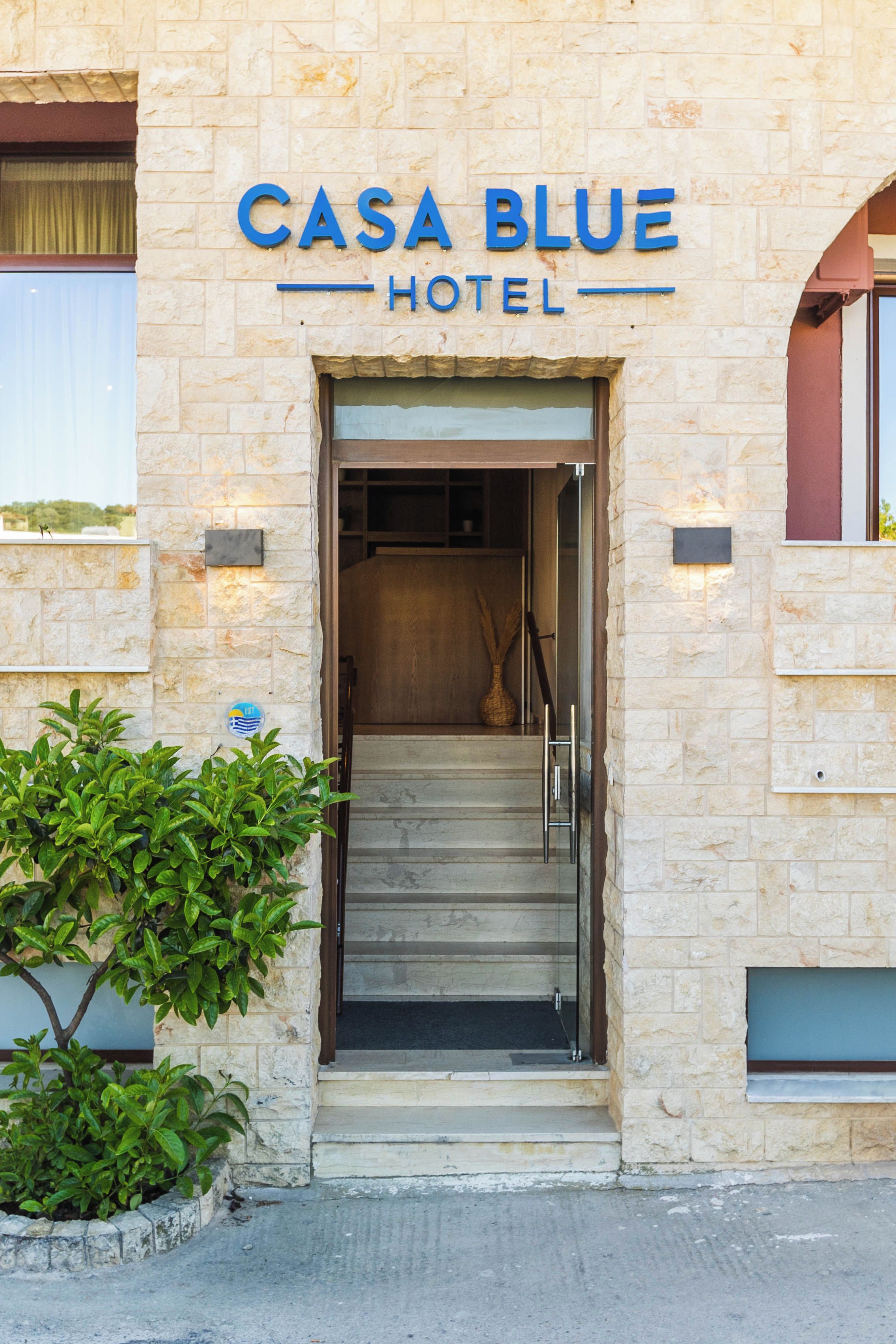 A entrada do Hotel Casa Blue, com fachada de pedra e uma placa sobre a porta.