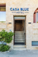 A entrada do Hotel Casa Blue, com fachada de pedra e uma placa sobre a porta.