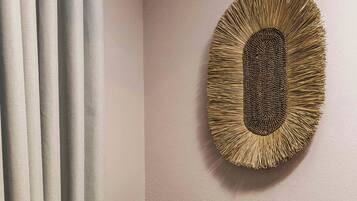 Uma poltrona cinza escura com pés de madeira, almofada marrom e uma peça de arte de parede trançada acima.
