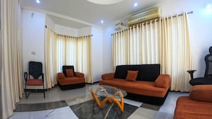 Sala de estar com sofá, mesa de centro de vidro e uma poltrona.