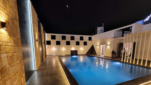 Piscina interna com piso ladrilhado e área lateral com cerca branca.