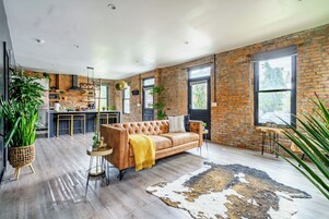 Uma sala de estar espaçosa com um sofá de couro, uma mesa de centro e um tapete grande.
