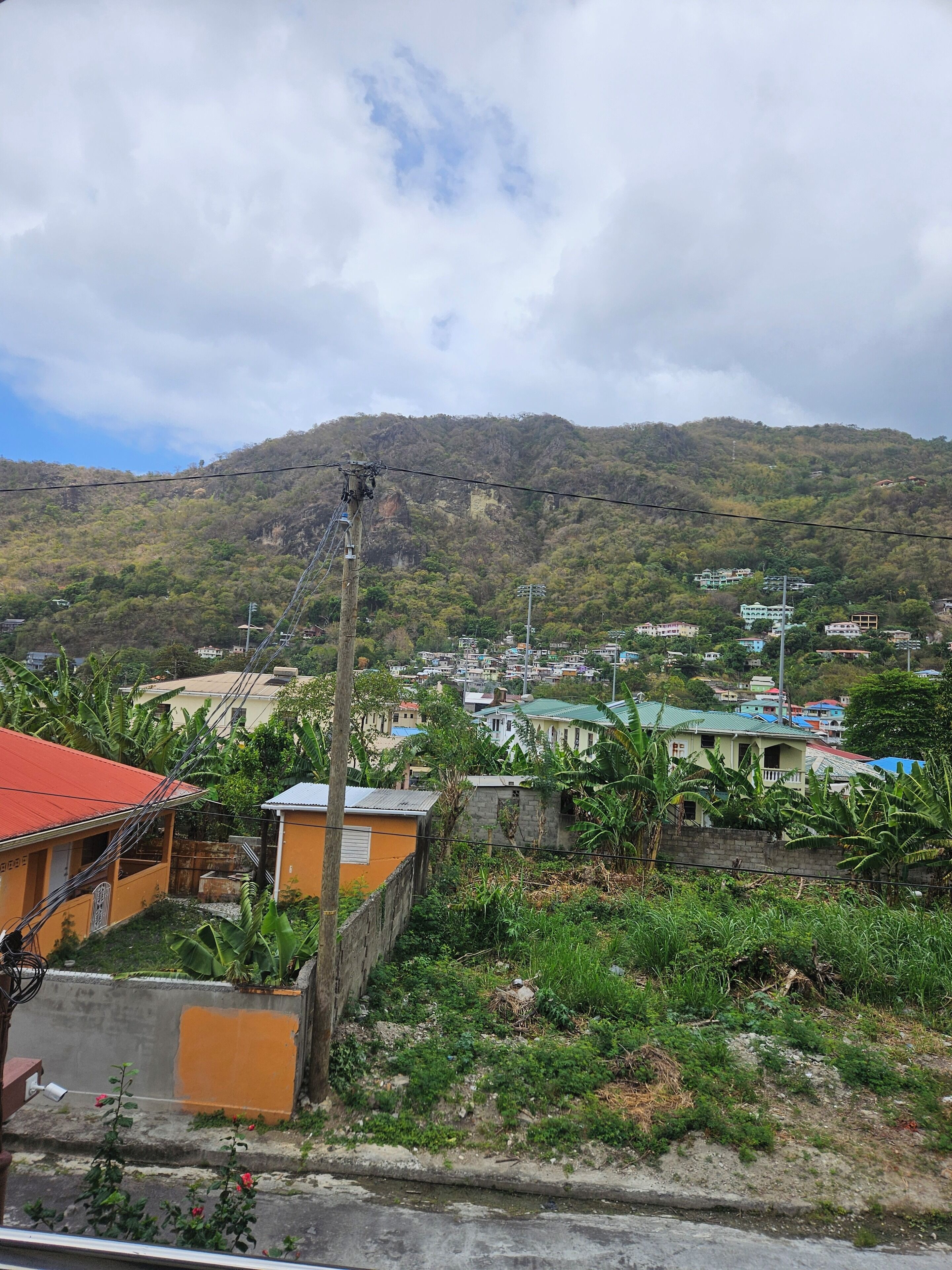 Zona residencial com casas, uma colina ao fundo e uma linha de energia em primeiro plano.