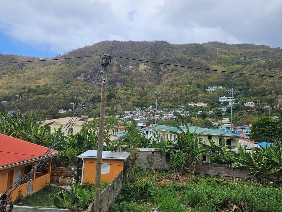Zona residencial com casas, uma colina ao fundo e uma linha de energia em primeiro plano.