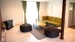Uma sala de estar moderna com um sofá verde, duas poltronas de couro, uma mesa de centro de madeira e uma lareira.