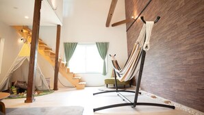 Um quarto espaçoso com uma rede, uma escada e uma estrutura tipo tenda.