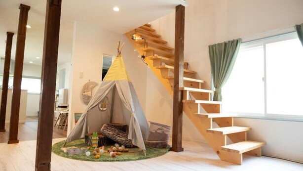 Quarto com escada de madeira, área de recreação com tenda e janela com cortinas.