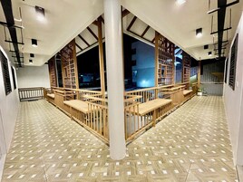 Um espaço amplo em ambiente interno, com piso estampado, bancos de madeira e vista através de grandes janelas.