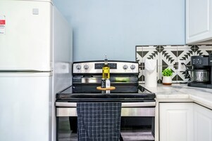 Cozinha equipada com fogão, geladeira e painel decorativo.