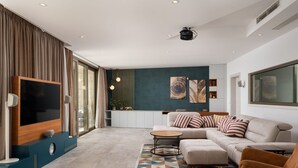 Uma sala de estar moderna com um sofá modular, uma mesa de centro e uma televisão de tela plana.