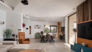 Uma sala de estar moderna com sofá, mesa de centro e área de jantar com cadeiras e mesa.