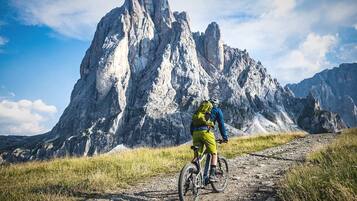 Ciclista de montanha numa trilha de terra, com uma montanha rochosa ao fundo.