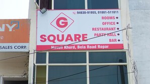 Um edifício com uma placa anunciando um estabelecimento 'SQUARE' que oferece quartos, espaço para escritórios, restaurante, salão de festas e bar.