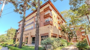 Um hotel com várias andares, varandas, um jardim bem cuidado e um céu limpo.